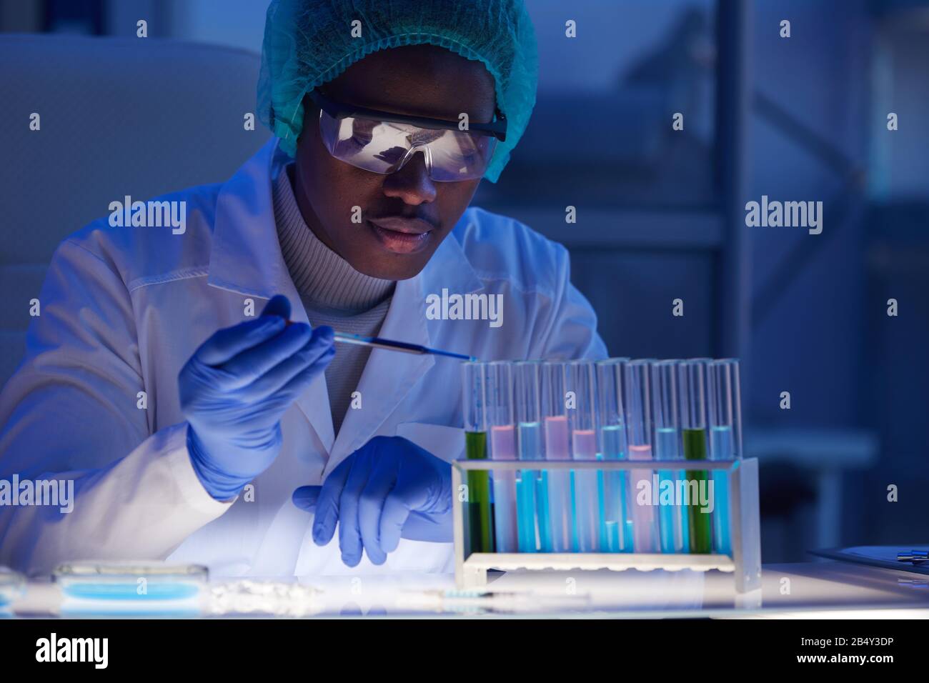 Horizontal chest up portrait of young male medical scientist sitting at ...