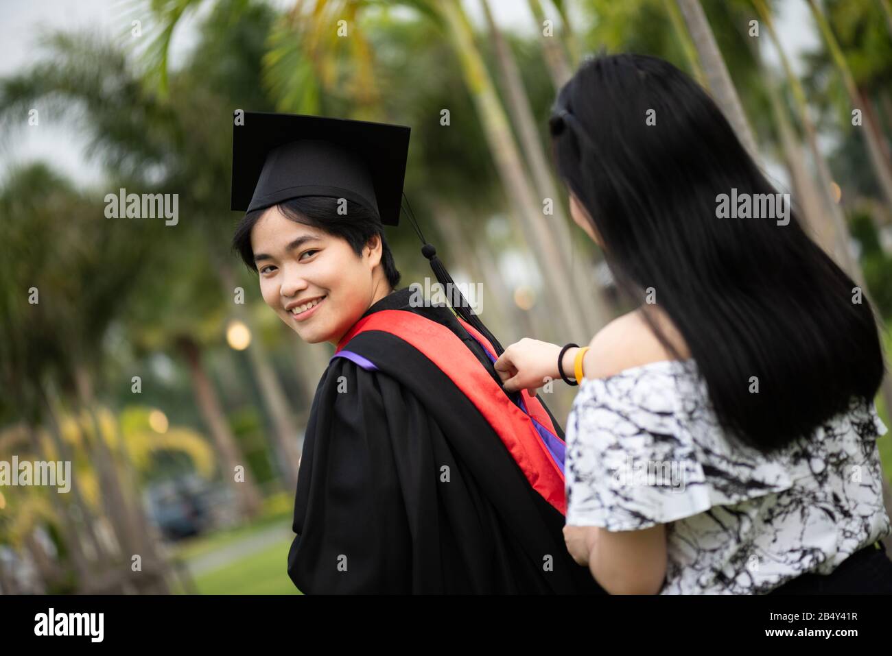 Graduation ceremony. Young female graduate with her friend congratulate ...