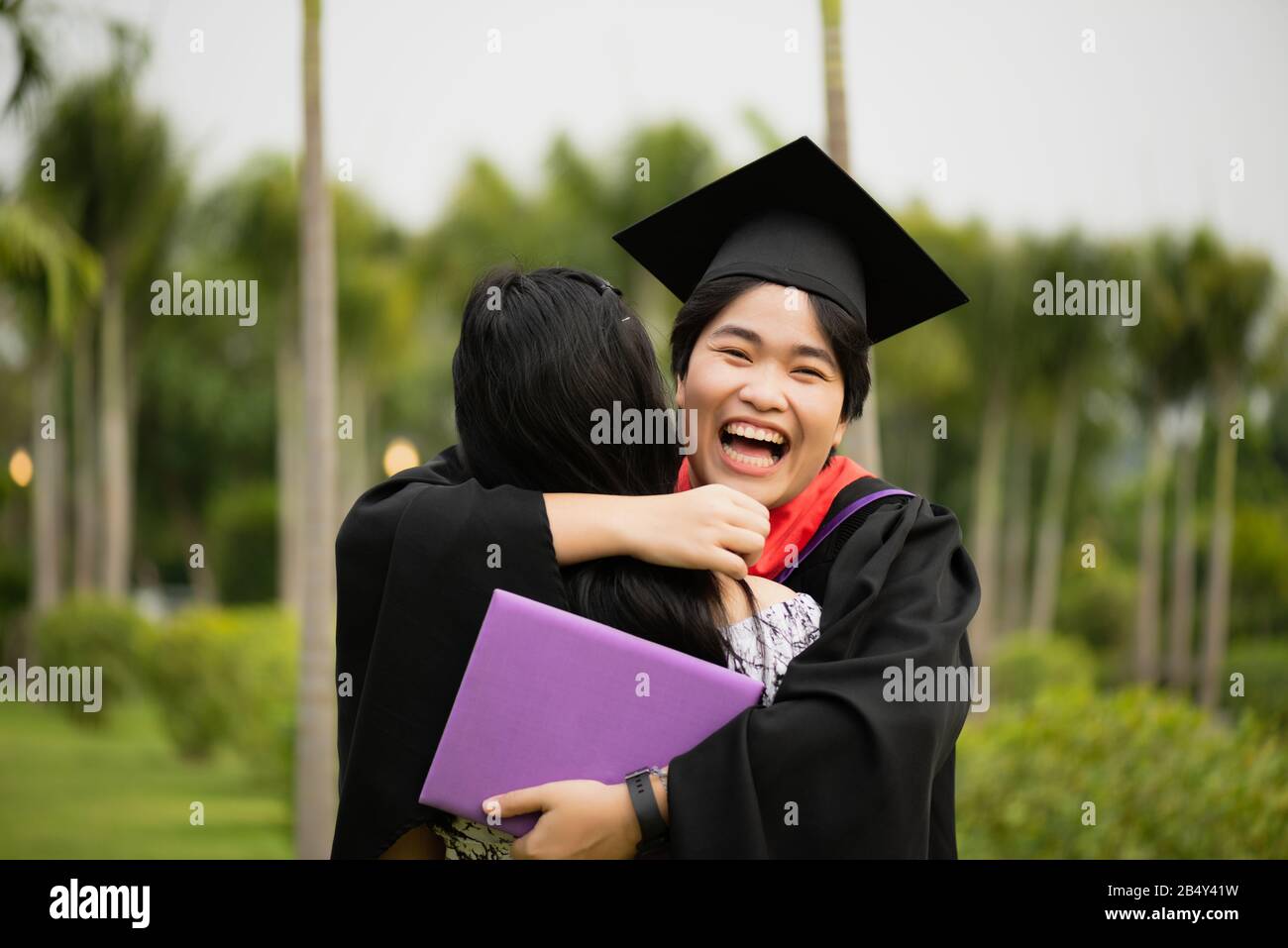 Graduation ceremony. Young female graduate hugging each other with her ...
