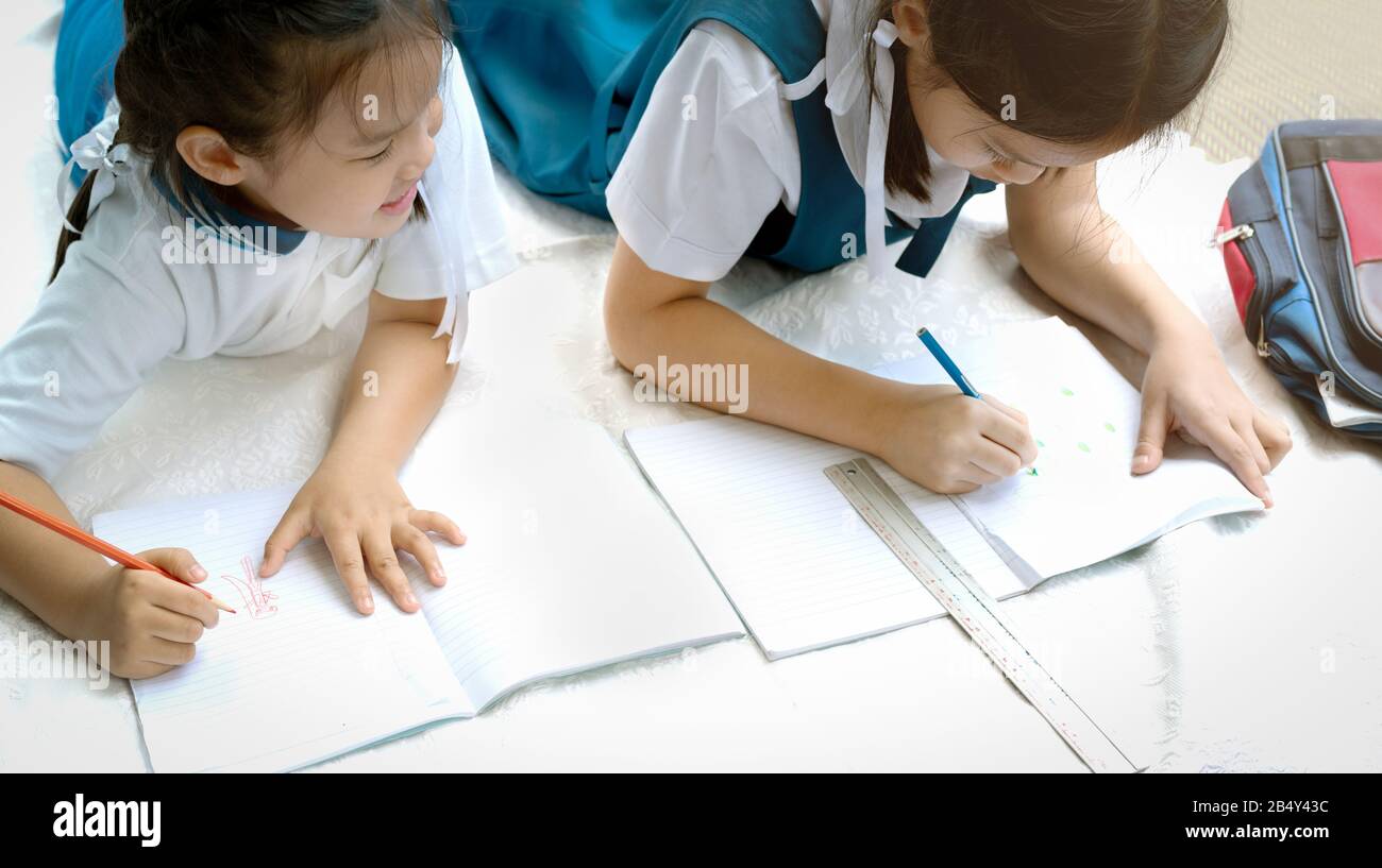 two sister girl writes a book. The decision of lessons. girl lay down ...