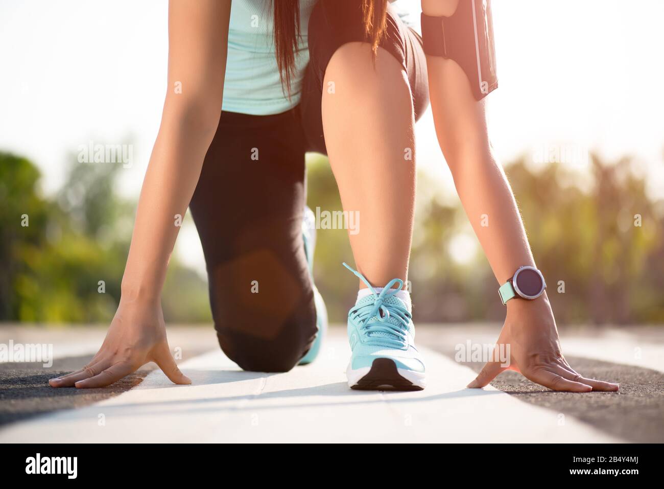 Front view of athletic women in running start pose on running track in ...