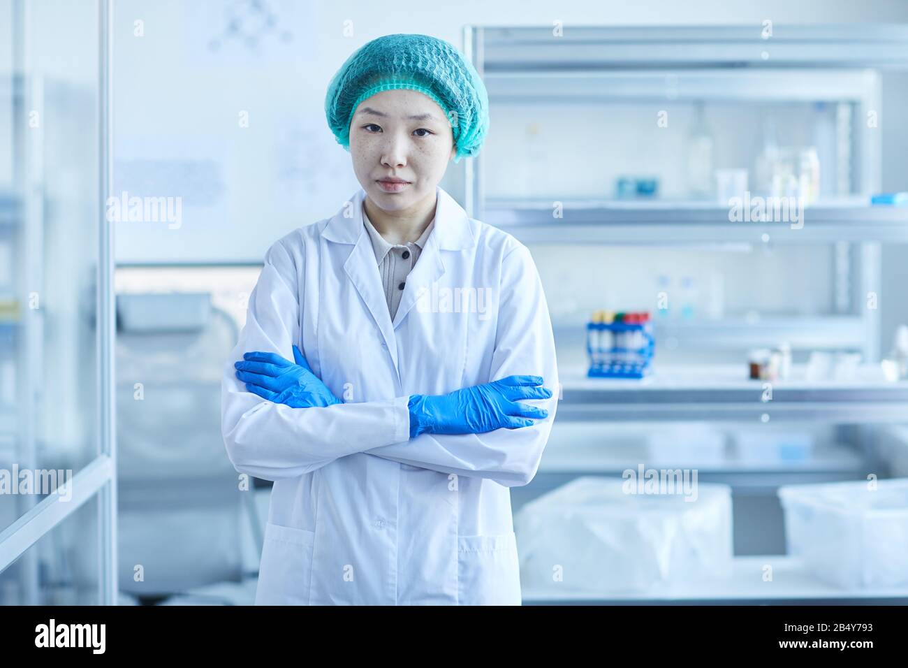 Horizontal medium portrait of young Asian female laboratory scientist standing with arms crossed ...