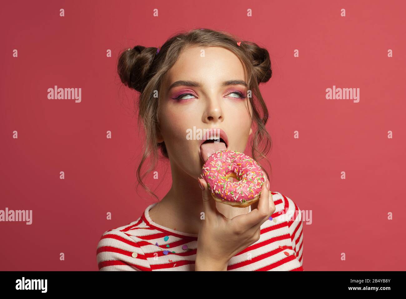 Funny woman eating donut and enjoying on pink background Stock Photo ...