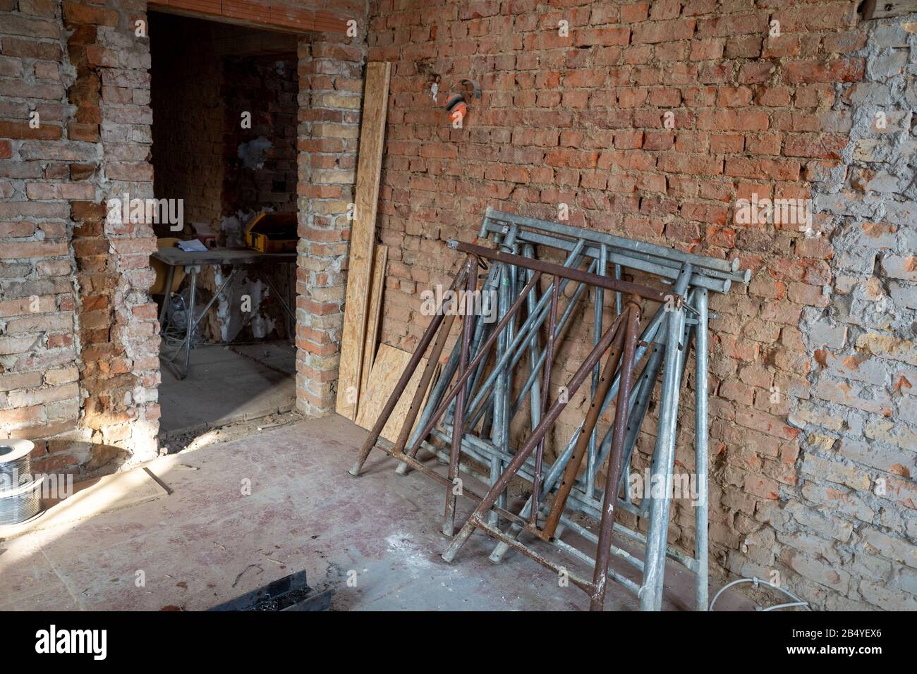 on a building site, two scaffolding trestles lean against a brick wall ...