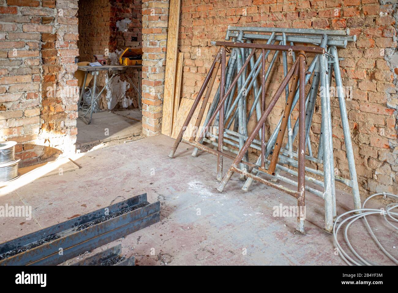 on a building site, two scaffolding trestles lean against a brick wall ...