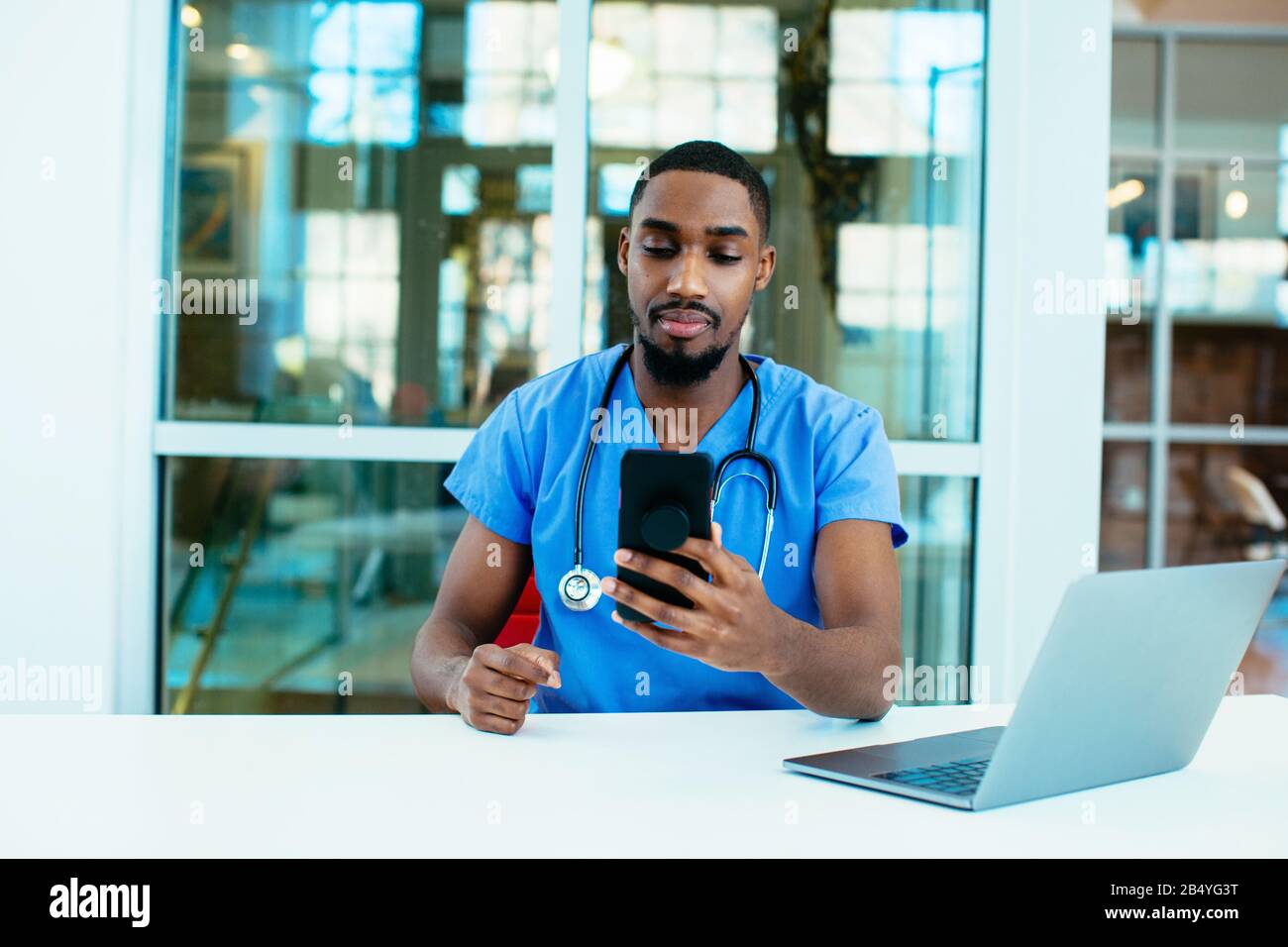 Portrait of a concerned male doctor or nurse wearing blue scrubs ...