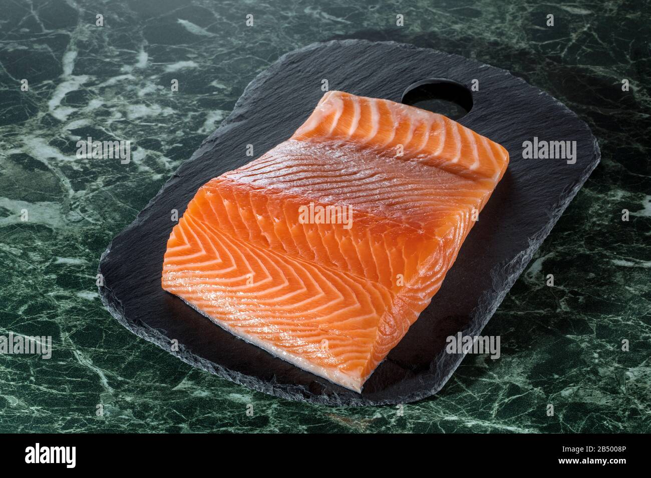 A raw salmon fillet on a black slate upon a marble table Stock Photo ...