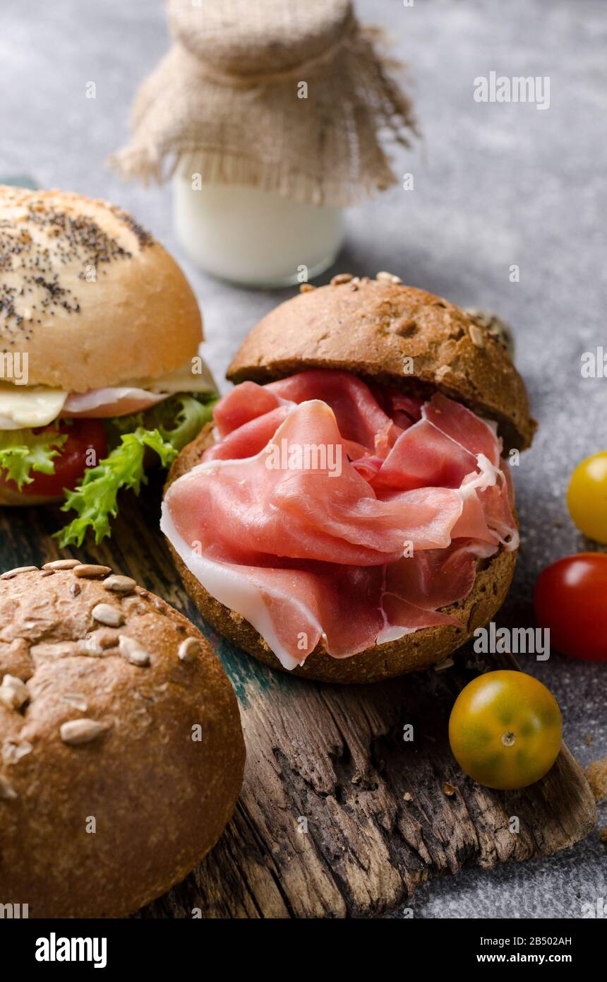 Delicious crispy burger bun with sliced ham on a vintage wooden cutting ...