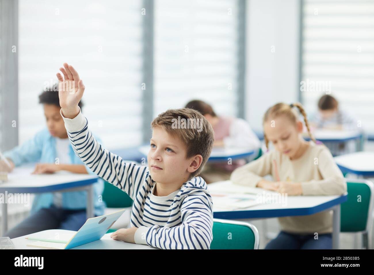Ten-year-old boy wearing striped sweatshirt ready to give answer ...