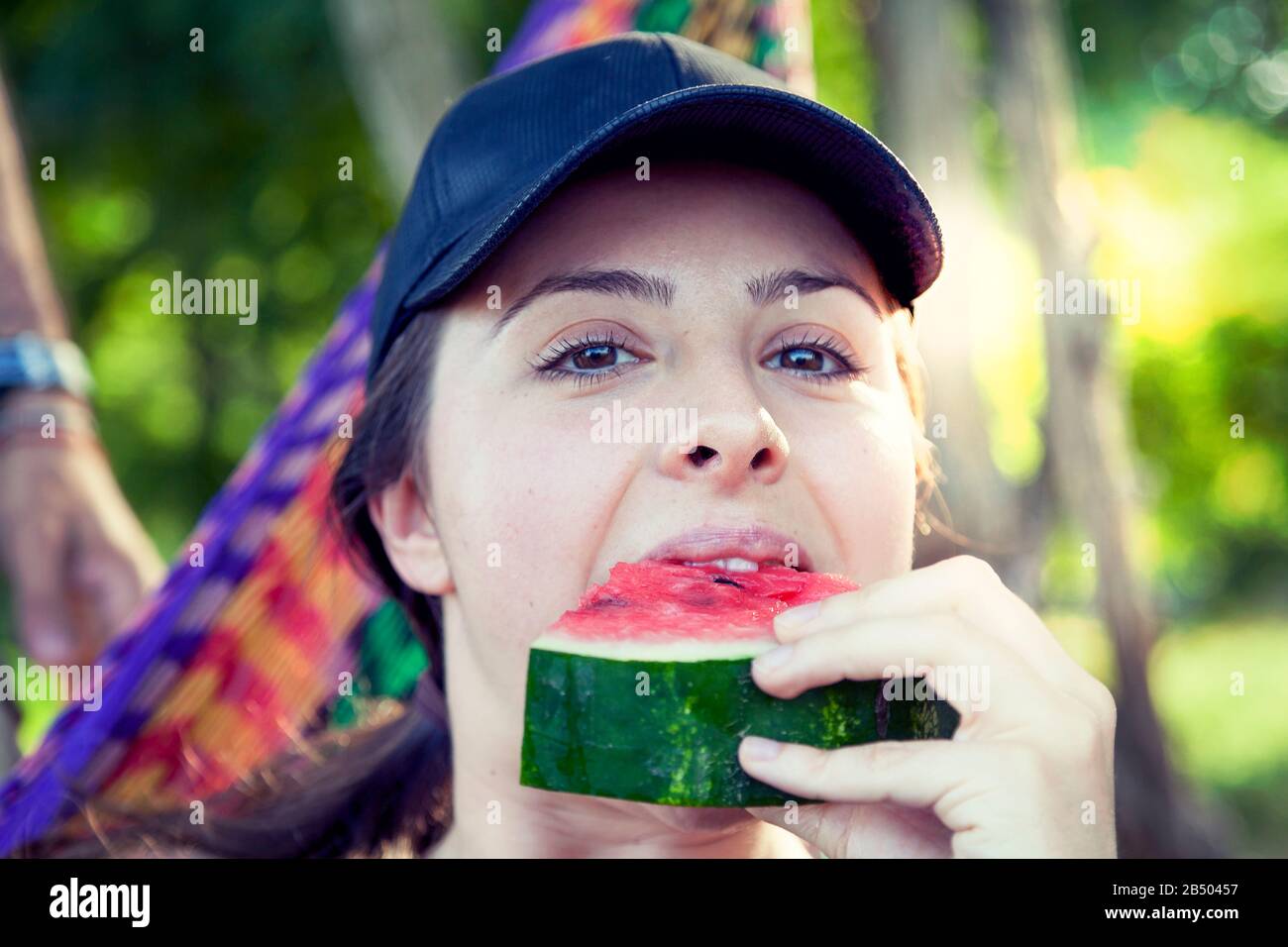 portrait of young pretty woman eating a slice of watermelon outdoors ...
