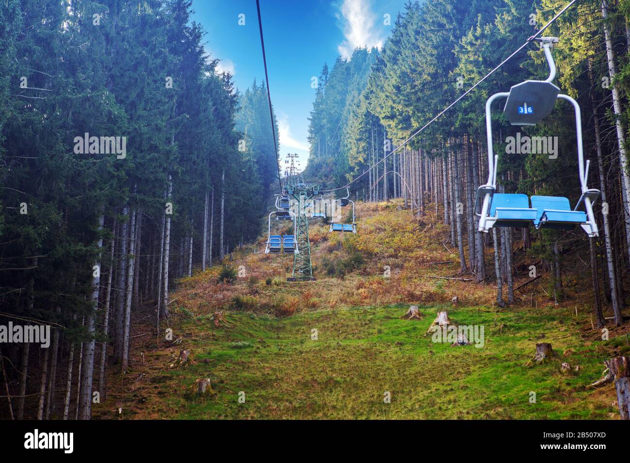 blue chair lifts going up the mountain through forest Stock Photo - Alamy