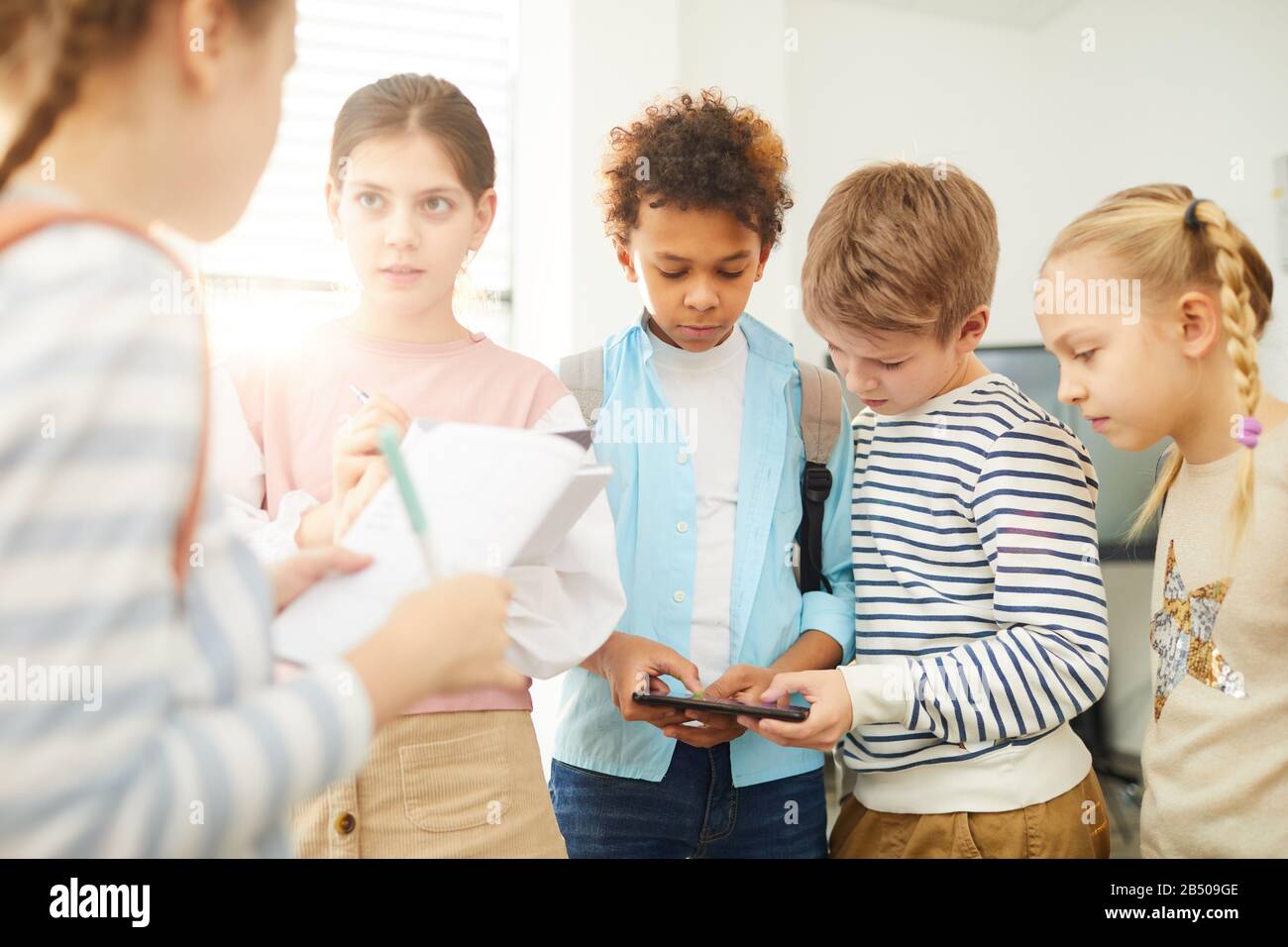 Horizontal medium shot of five modern middle school students standing ...