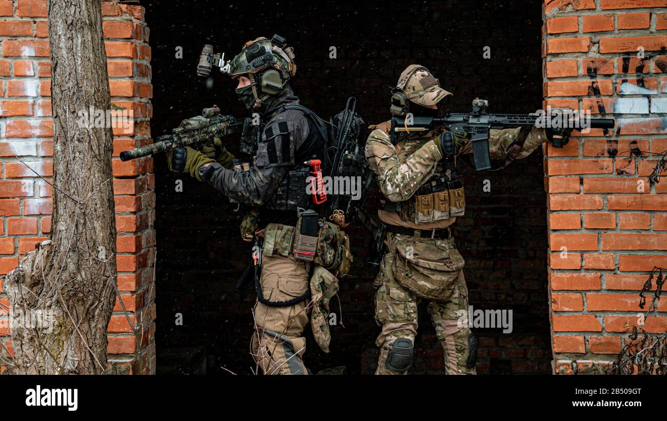Two men in camouflage cloth and black uniform with machineguns stand ...