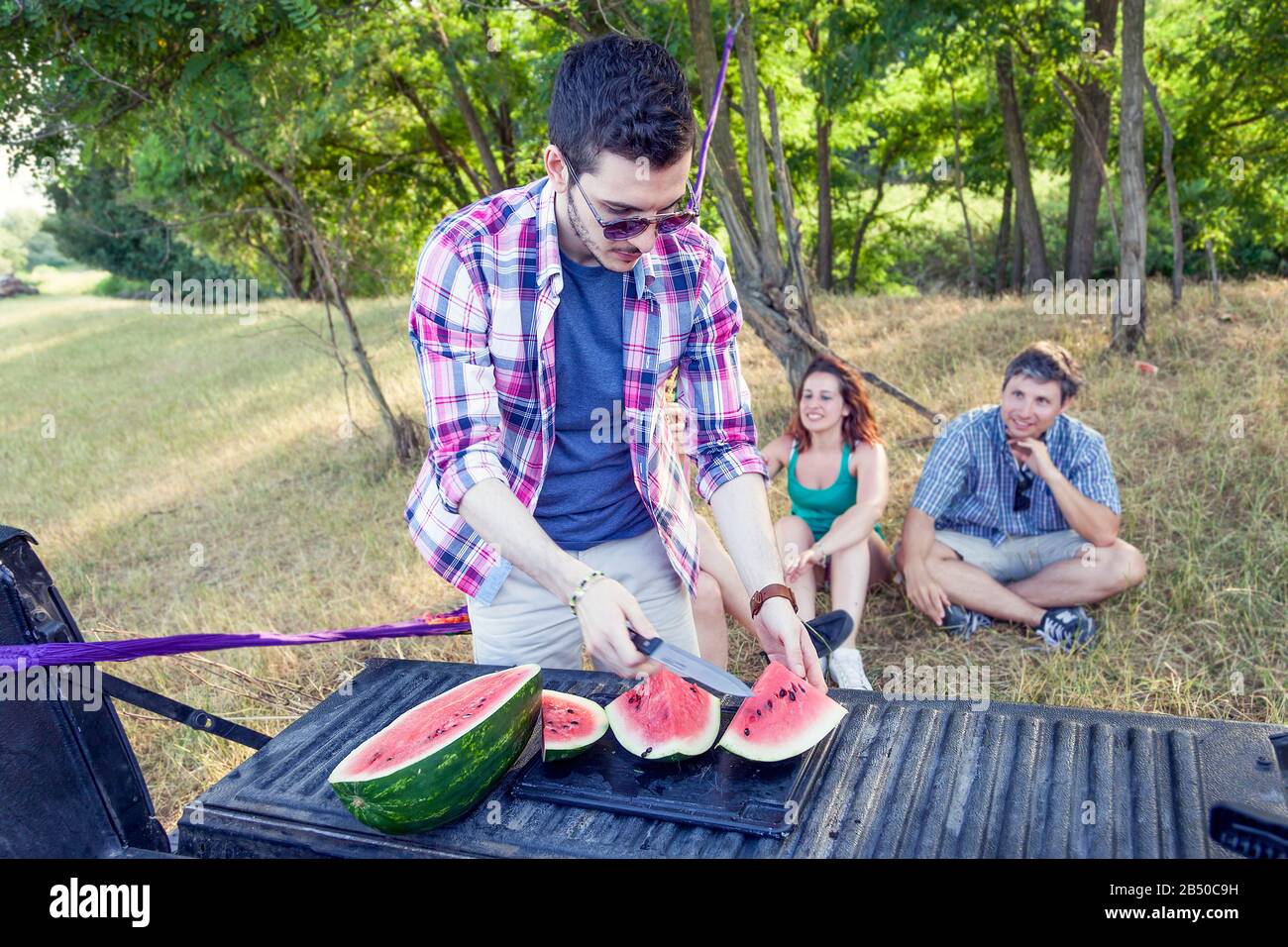 group of young adults have fun and eating slices of watermelon outdoors ...