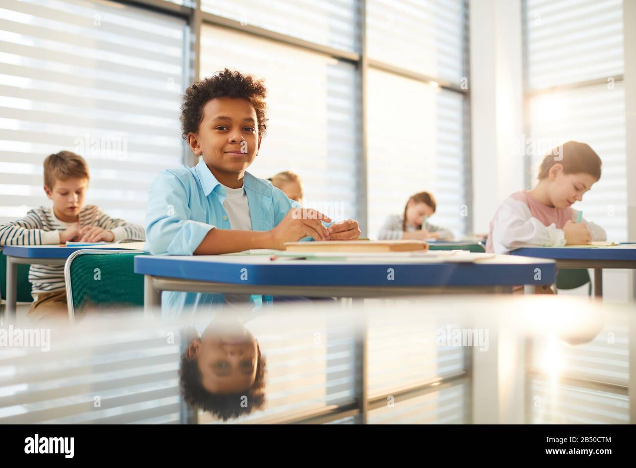 Horizontal shot of young middle school student sitting at desk in ...