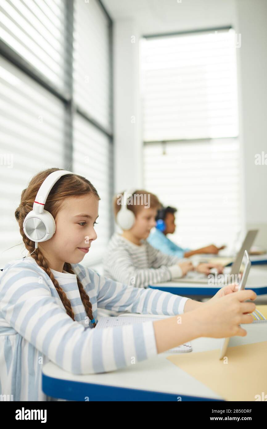 Young students sitting in classroom using modern gadgets during lesson ...
