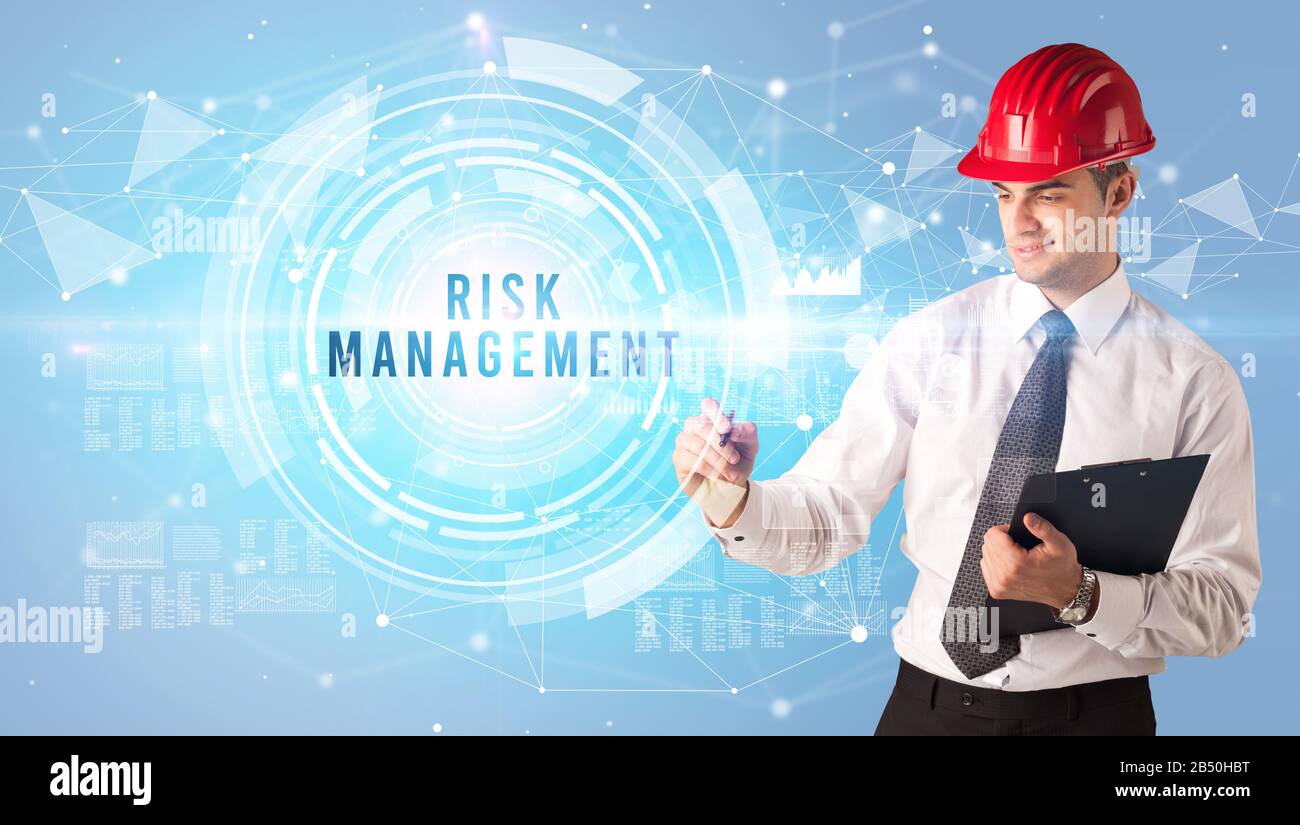 Handsome businessman with helmet drawing RISK MANAGEMENT inscription ...