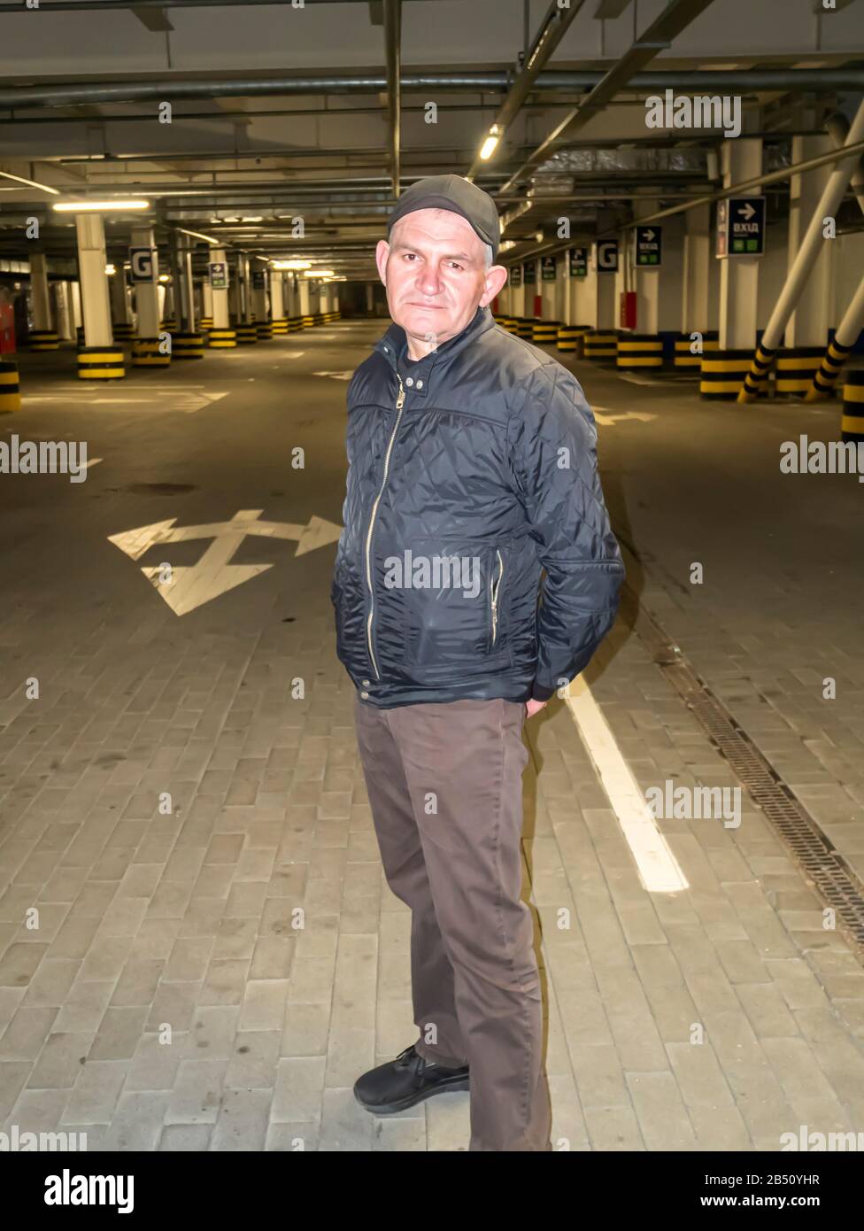 A man with a baseball cap in an underground car parking. People ...