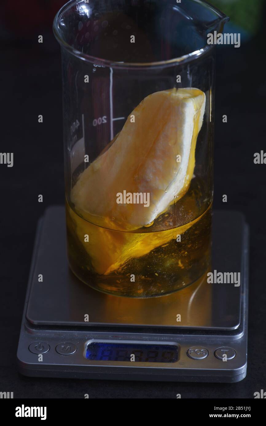 Solid butter and plant based oil mixed in glass flask on weighing scale ...