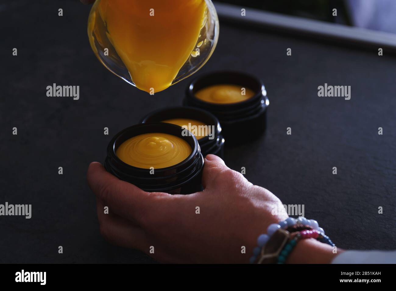 Female hands pouring freshly made natural diy skin cream into black ...