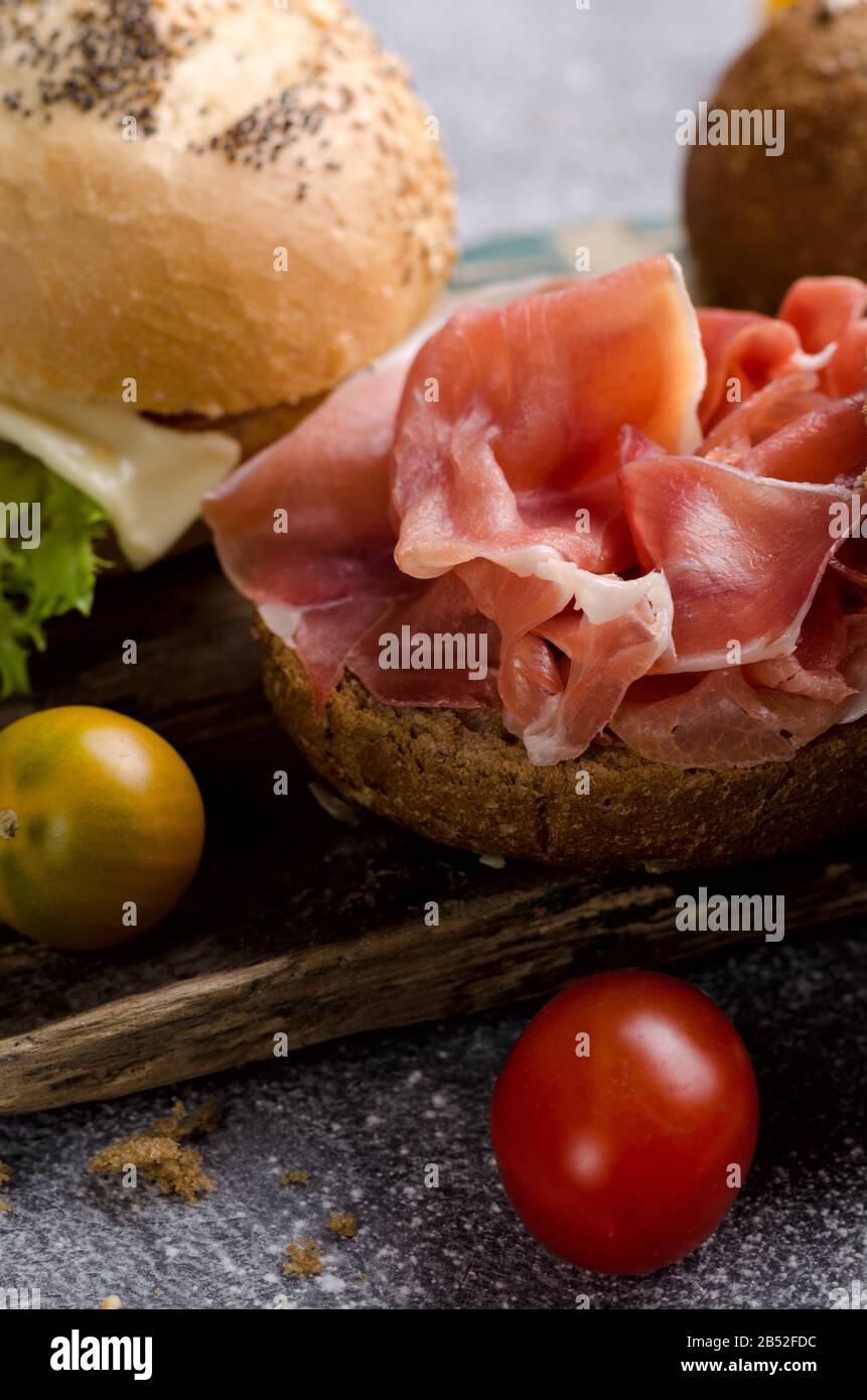 Delicious crispy burger bun with sliced ham on a vintage wooden cutting ...