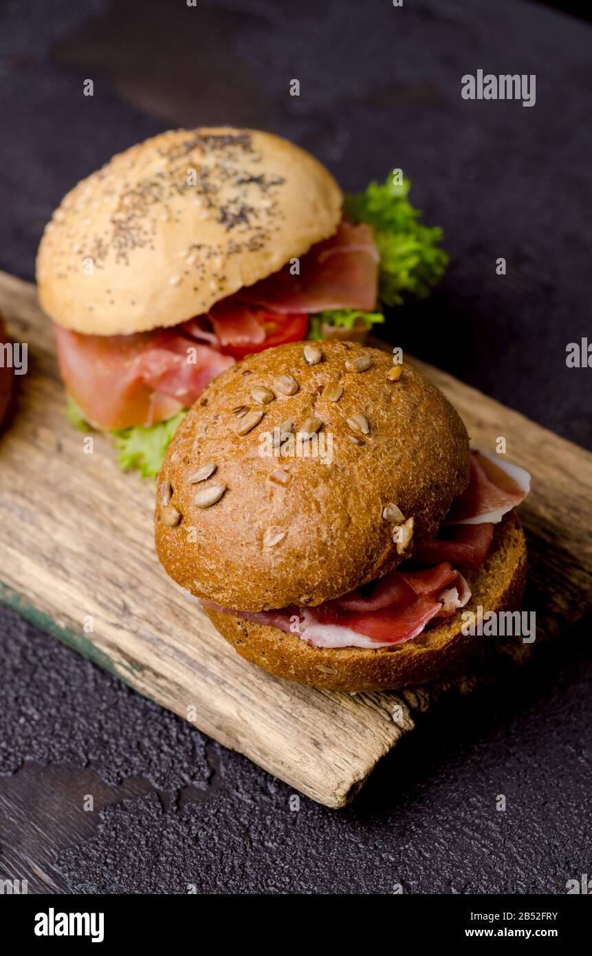 Delicious crispy burger bun with sliced ham on a vintage wooden cutting ...