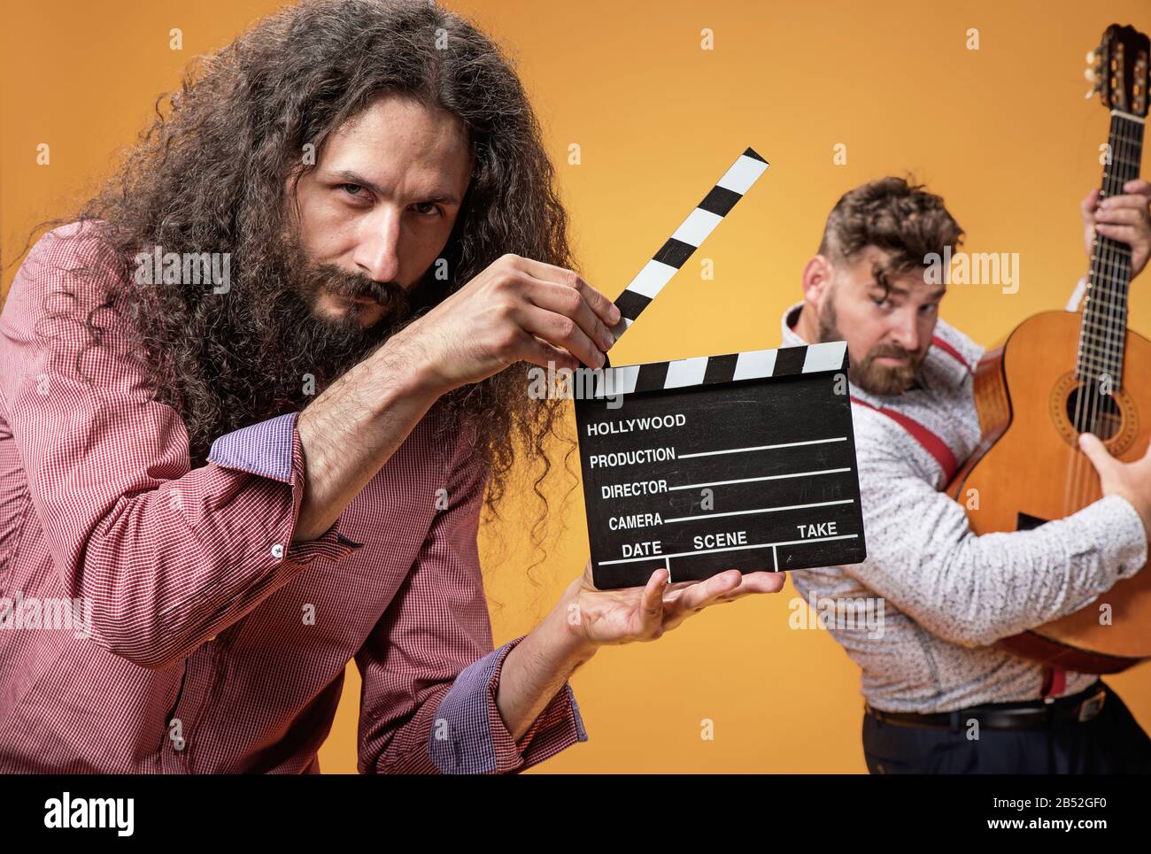 Skinny nerd holding a clappenboard on a filmset Stock Photo - Alamy