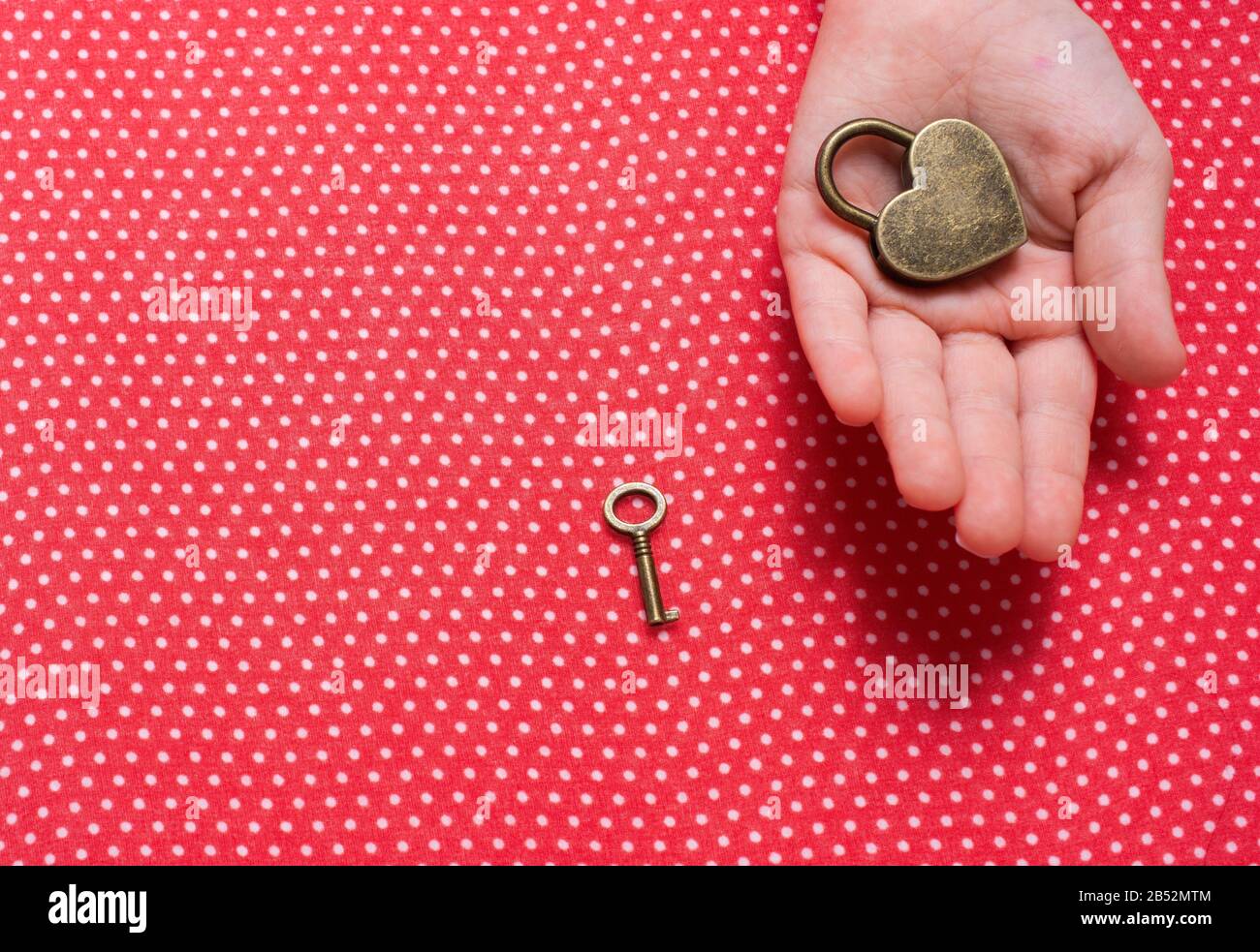 Hand holding a heart shaped lock and key on a red background Stock ...