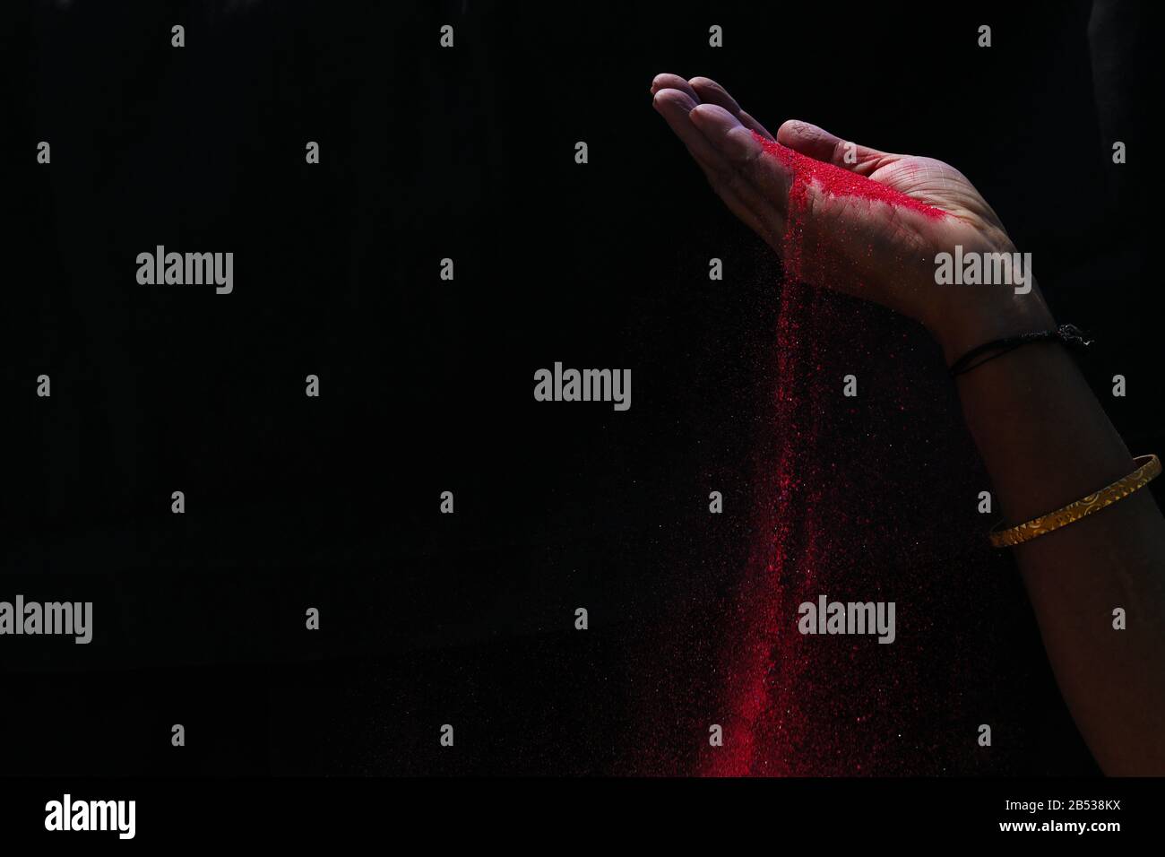 Closeup hand red colour holi powder splash at black backgrounds Stock ...