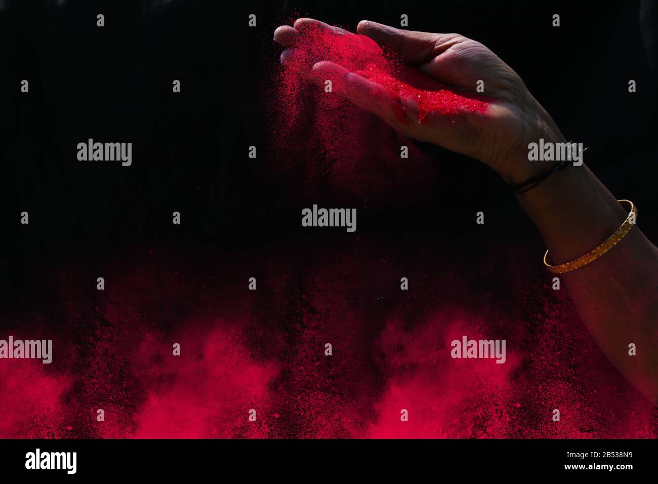 Closeup hand red colour holi powder splash at black backgrounds Stock ...