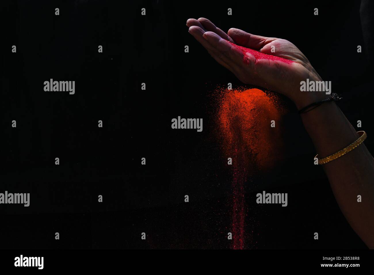 Closeup hand red colour holi powder splash at black background Stock ...