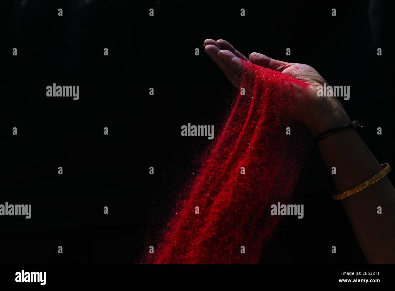 Closeup hand red colour holi powder splash at black background Stock ...