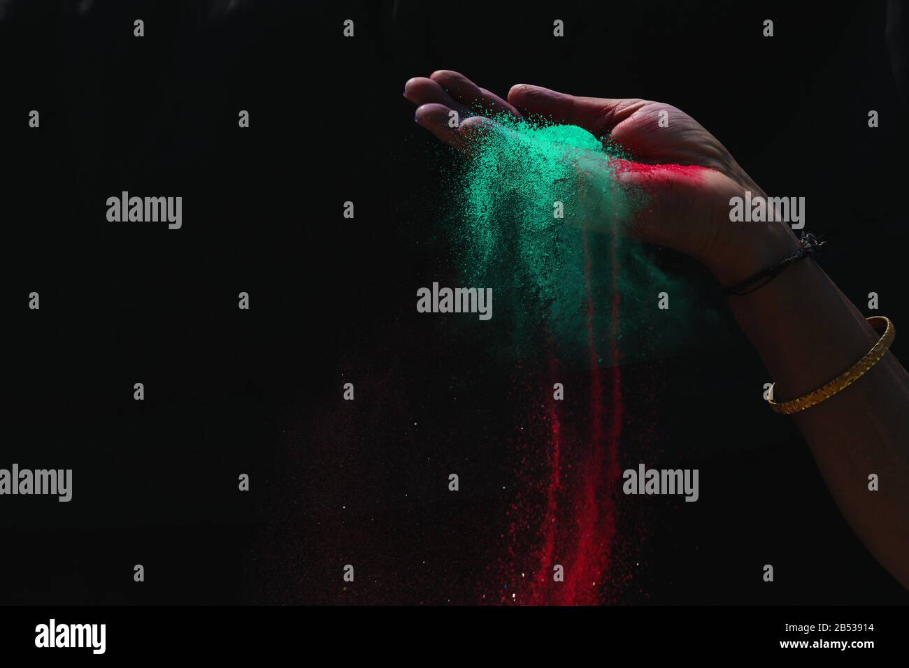 Indian woman hand colourful holi powder splash at black backgrounds ...