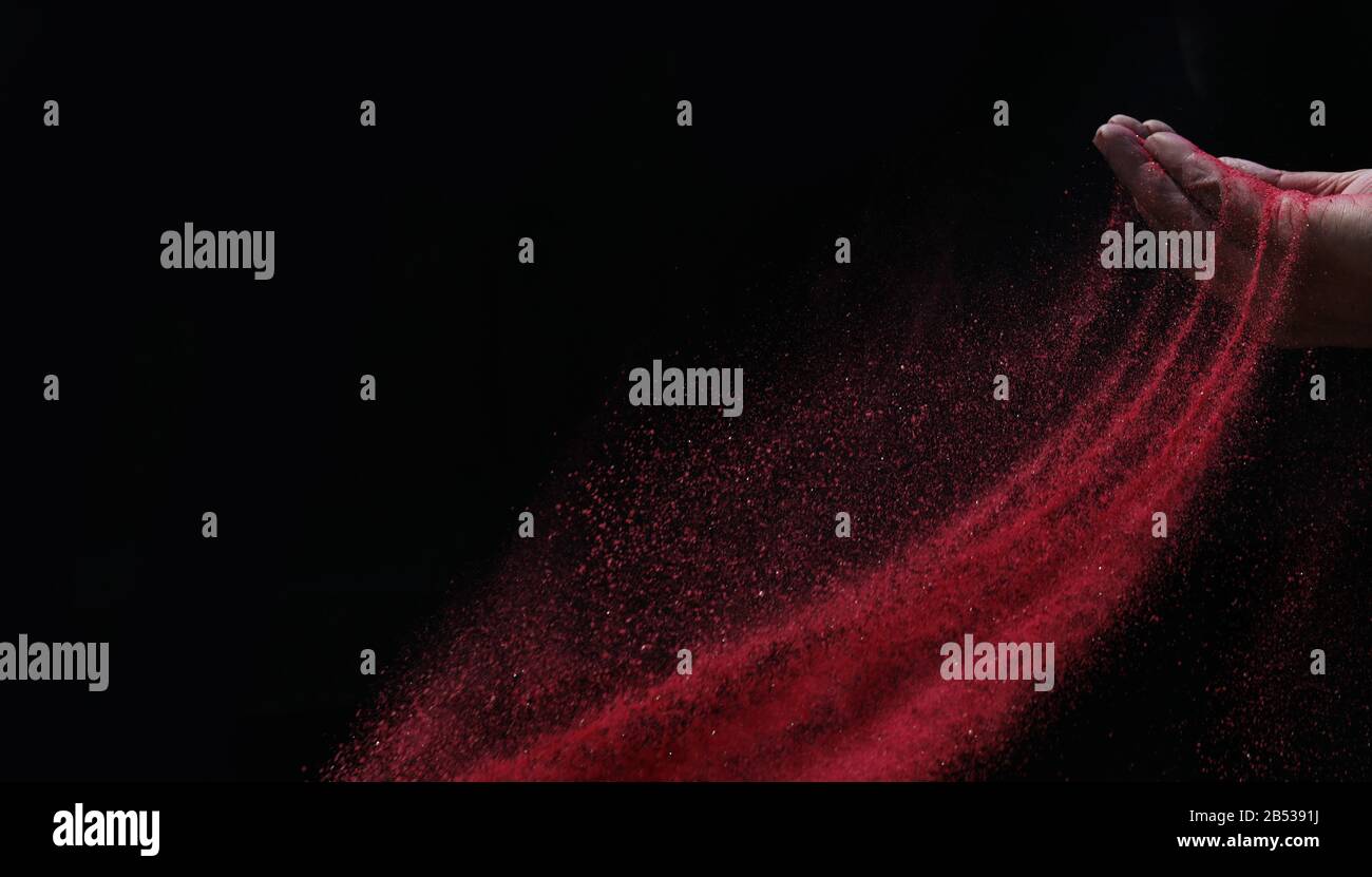 Closeup hand red colour holi powder splash at black background Stock ...