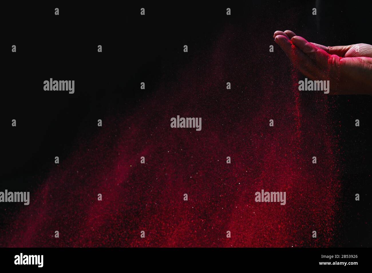 Closeup hand red colour holi powder splash at black background Stock ...