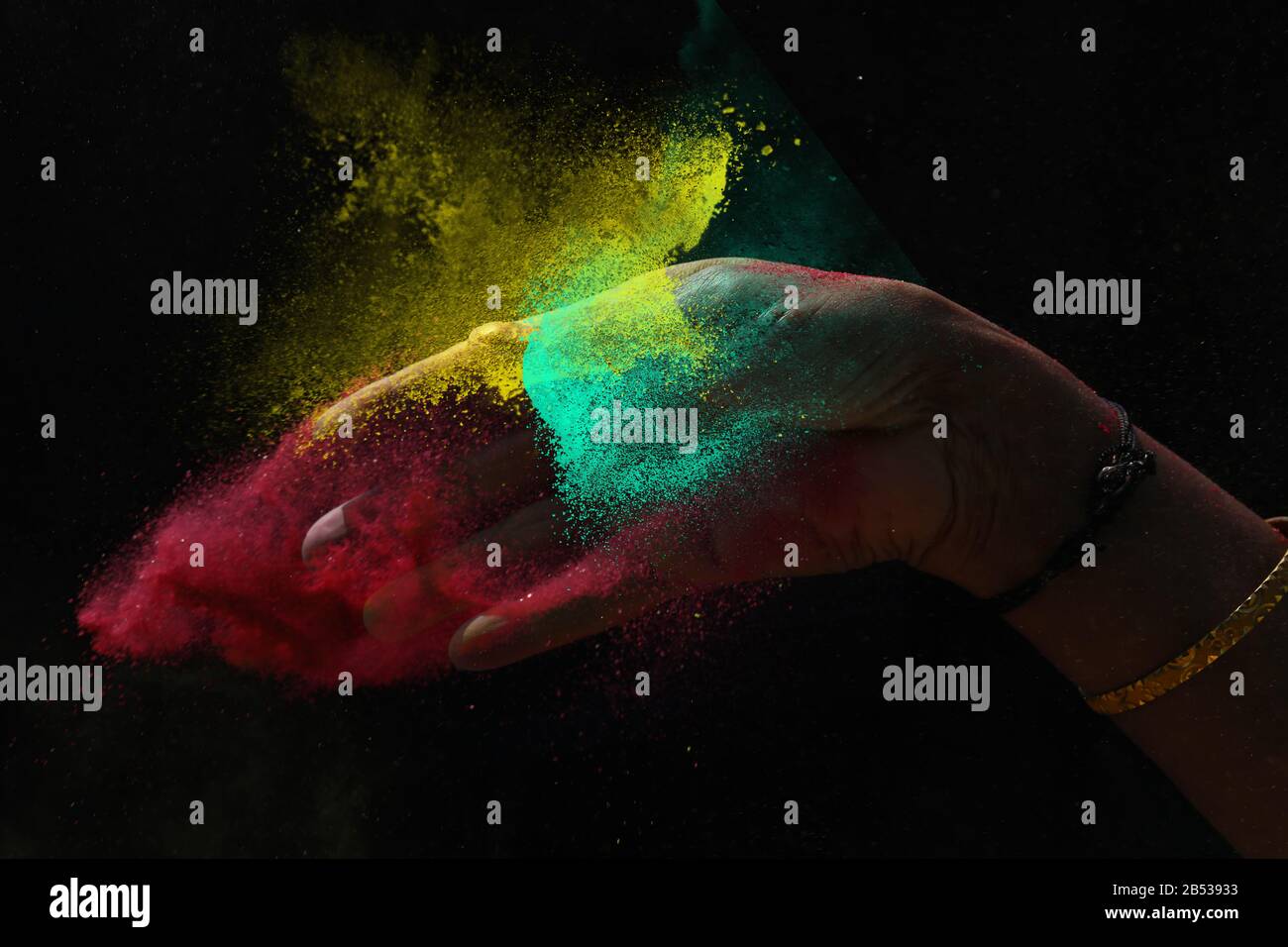 Indian woman hand colourful holi powder splash at black background ...
