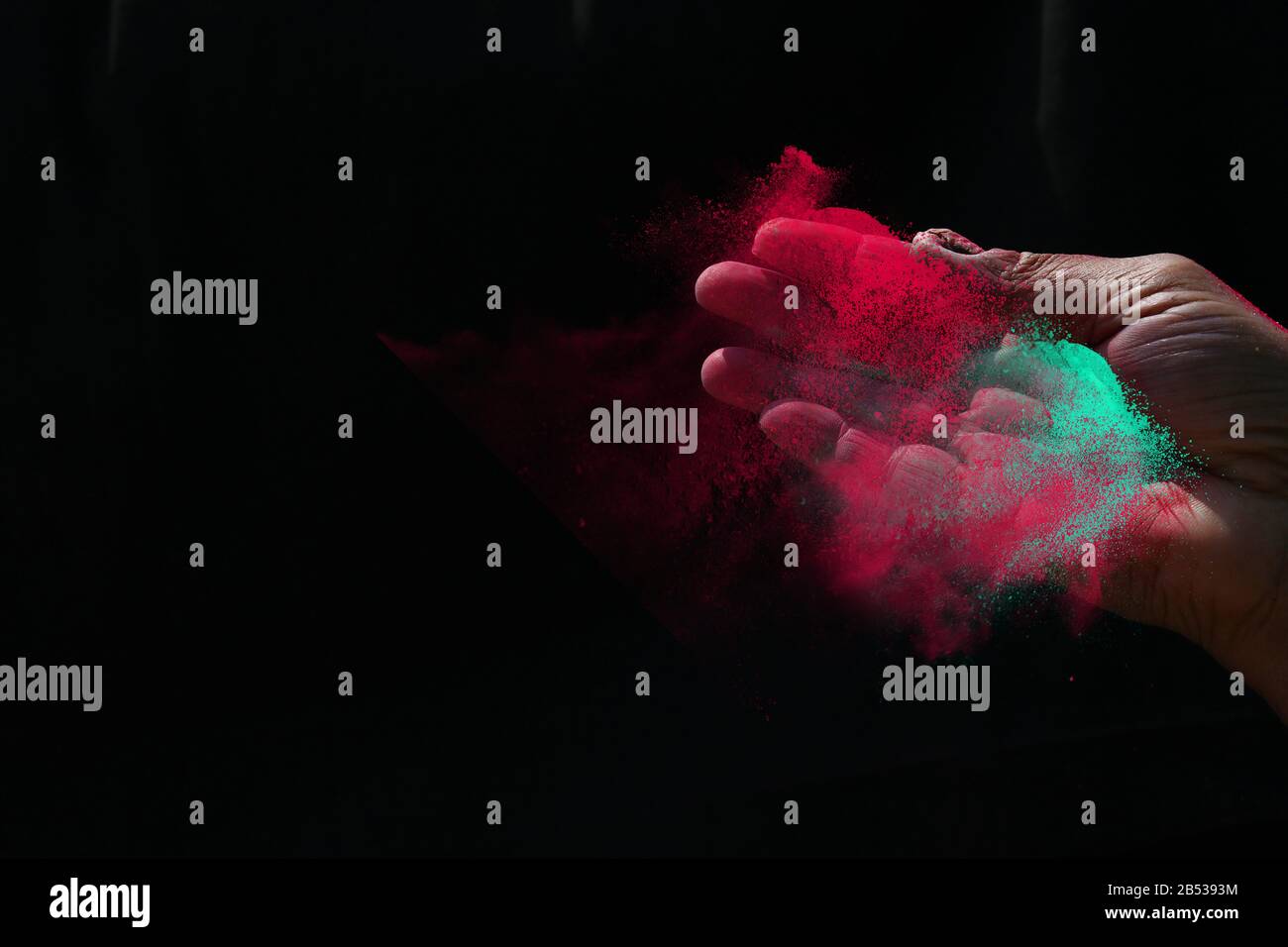 Indian woman hand colourful holi powder splash at black backgrounds ...