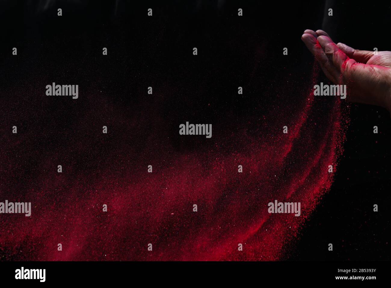 Closeup hand red colour holi powder splash at black background Stock ...