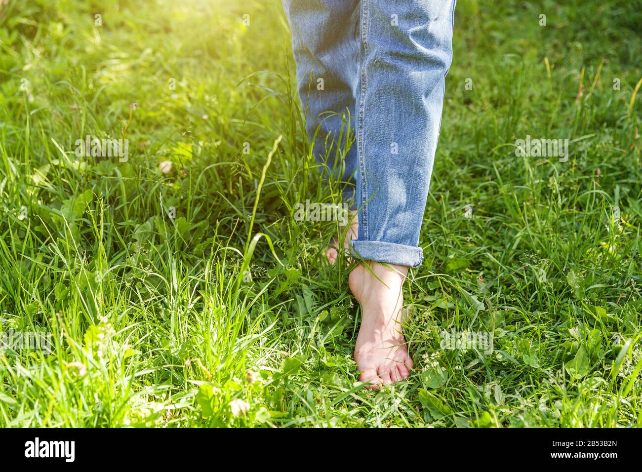 Two beautiful female feet walking on grass in sunny summer morning ...