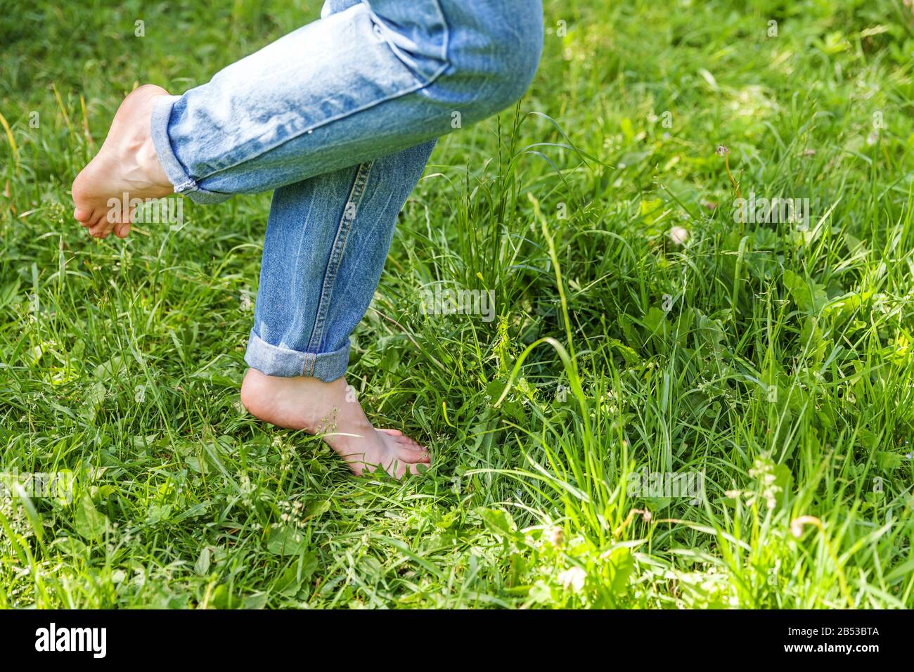 Two beautiful female feet walking on grass in sunny summer morning ...