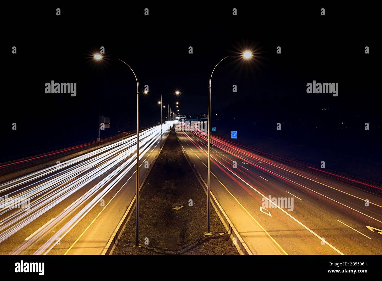 Speed traffic - light trails on highway at night. Cars exiting highway ...