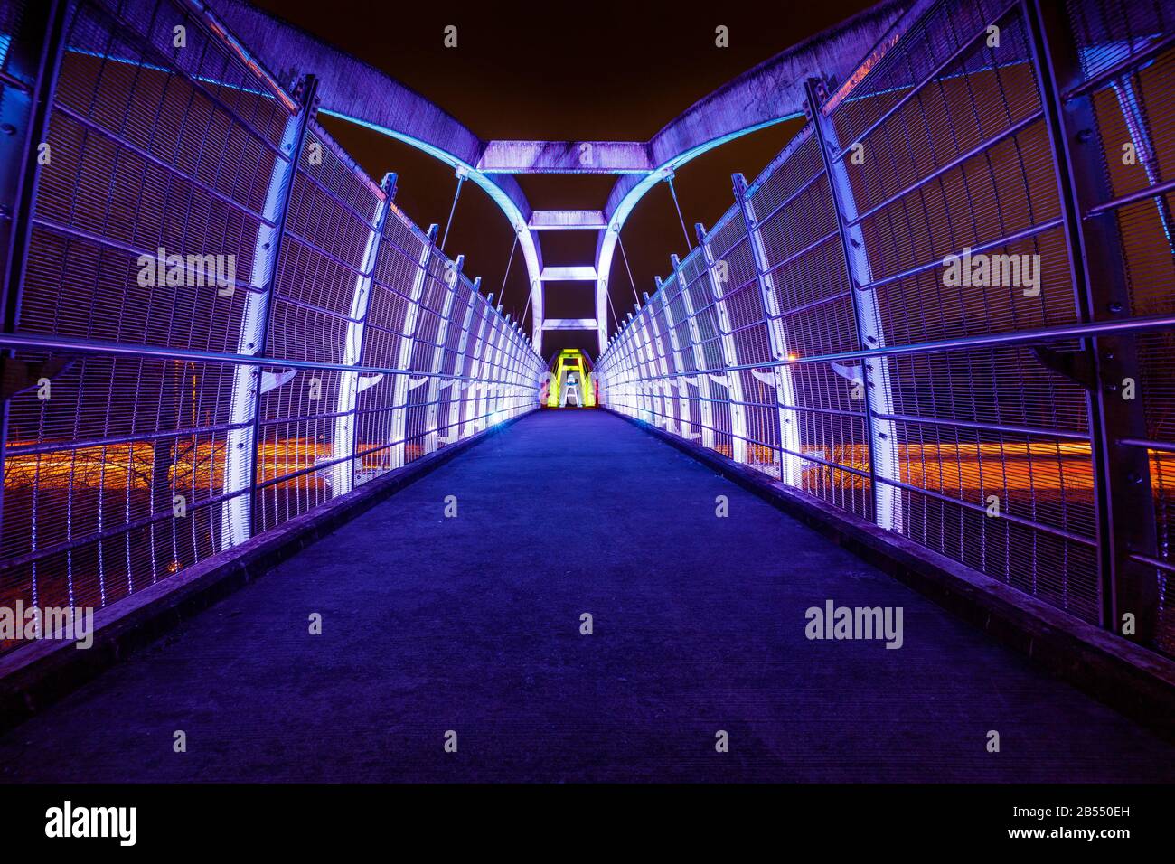 Bright white LEDs illuminate pedestrian walkway over highway at night ...