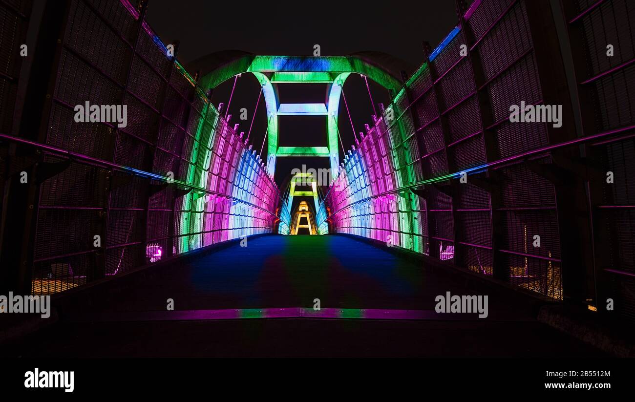 Bright colors illuminate pedestrian walkway over highway at night Stock ...