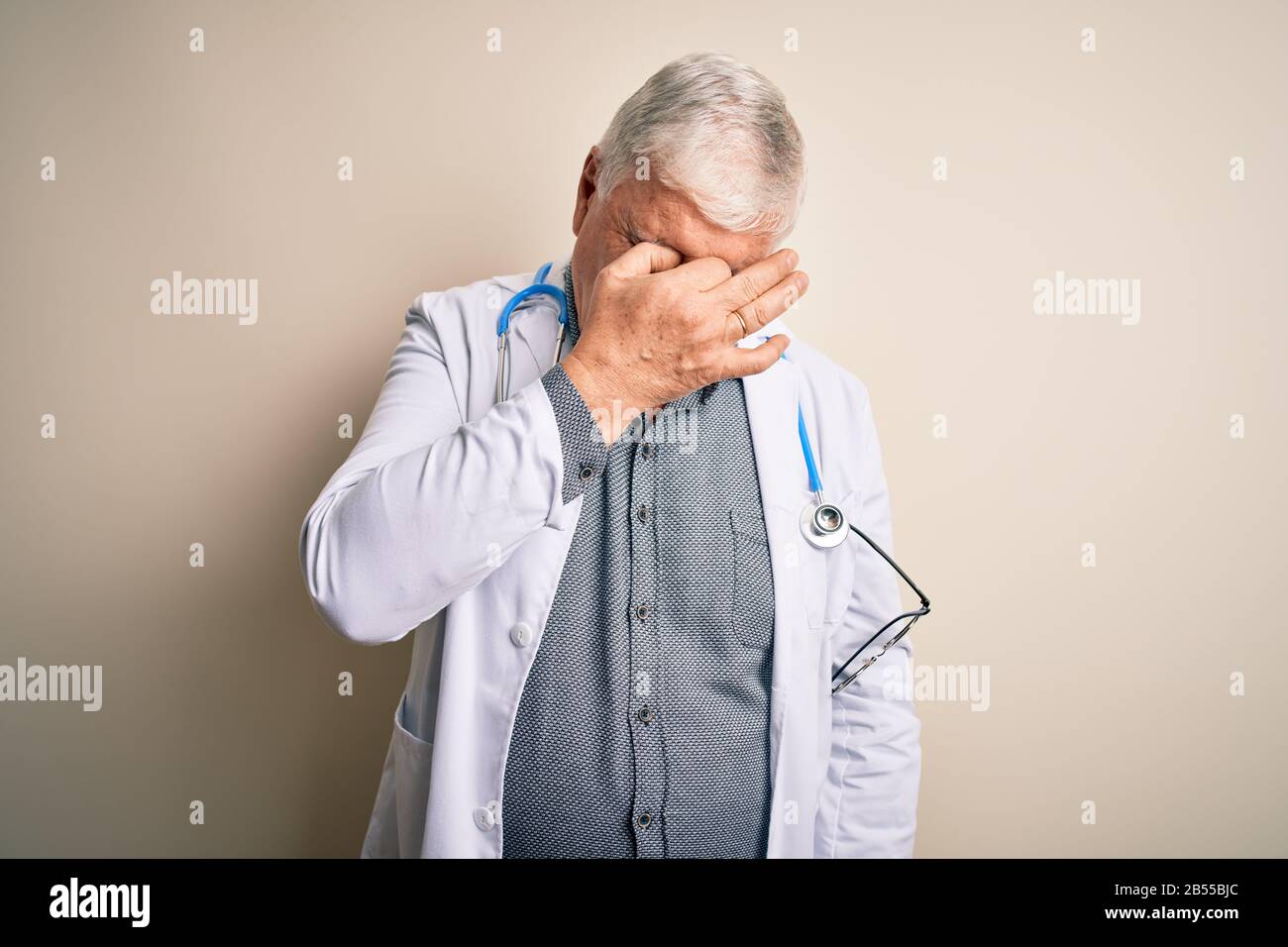 Senior handsome hoary doctor man wearing coat and stethoscope over ...