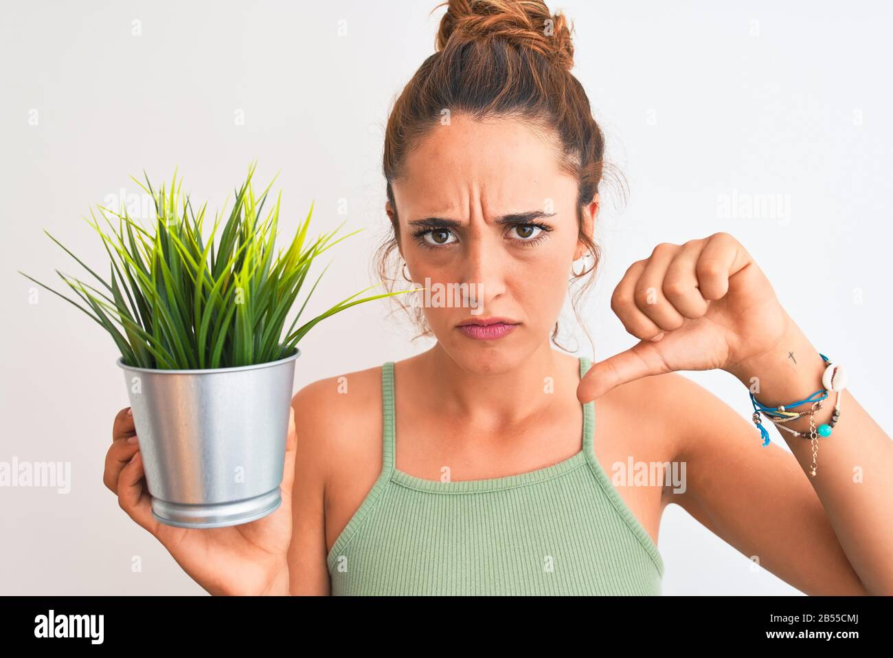 Young redhead woman holding plant pot over isolated background with ...