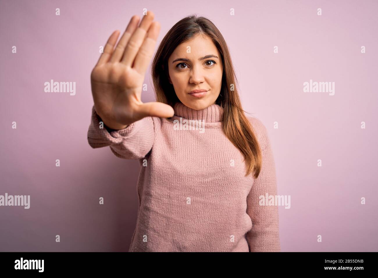 Beautiful young woman wearing turtleneck sweater over pink isolated ...