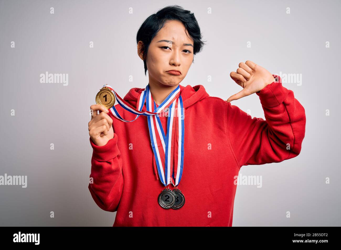 Young beautiful asian girl winner wearing medals over isolated white ...
