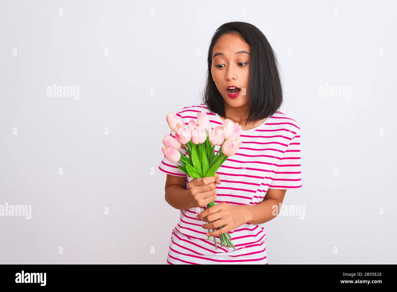 Young chinese woman holding bouquet of roses standing over isolated ...