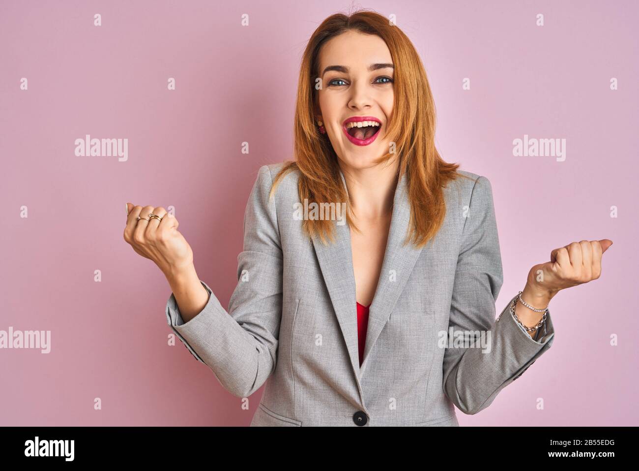 Young caucasian business woman wearing a suit over isolated pink ...