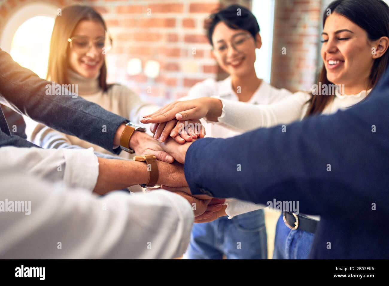 Group of business workers standing with hands together at the office ...
